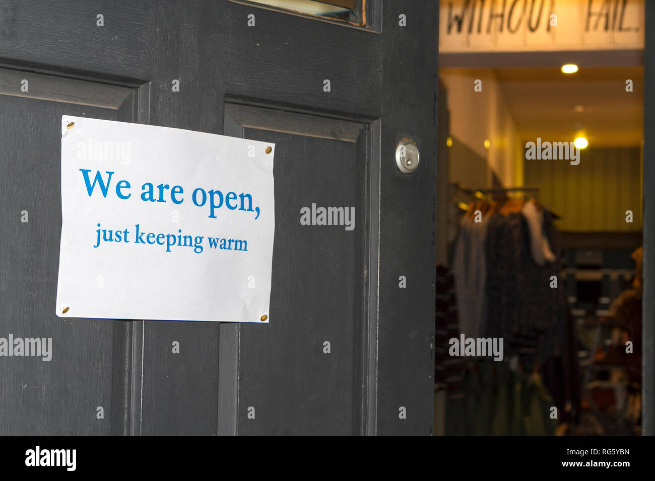 Clothing retail shop store outlet with 'We are open, just keeping warm ...
