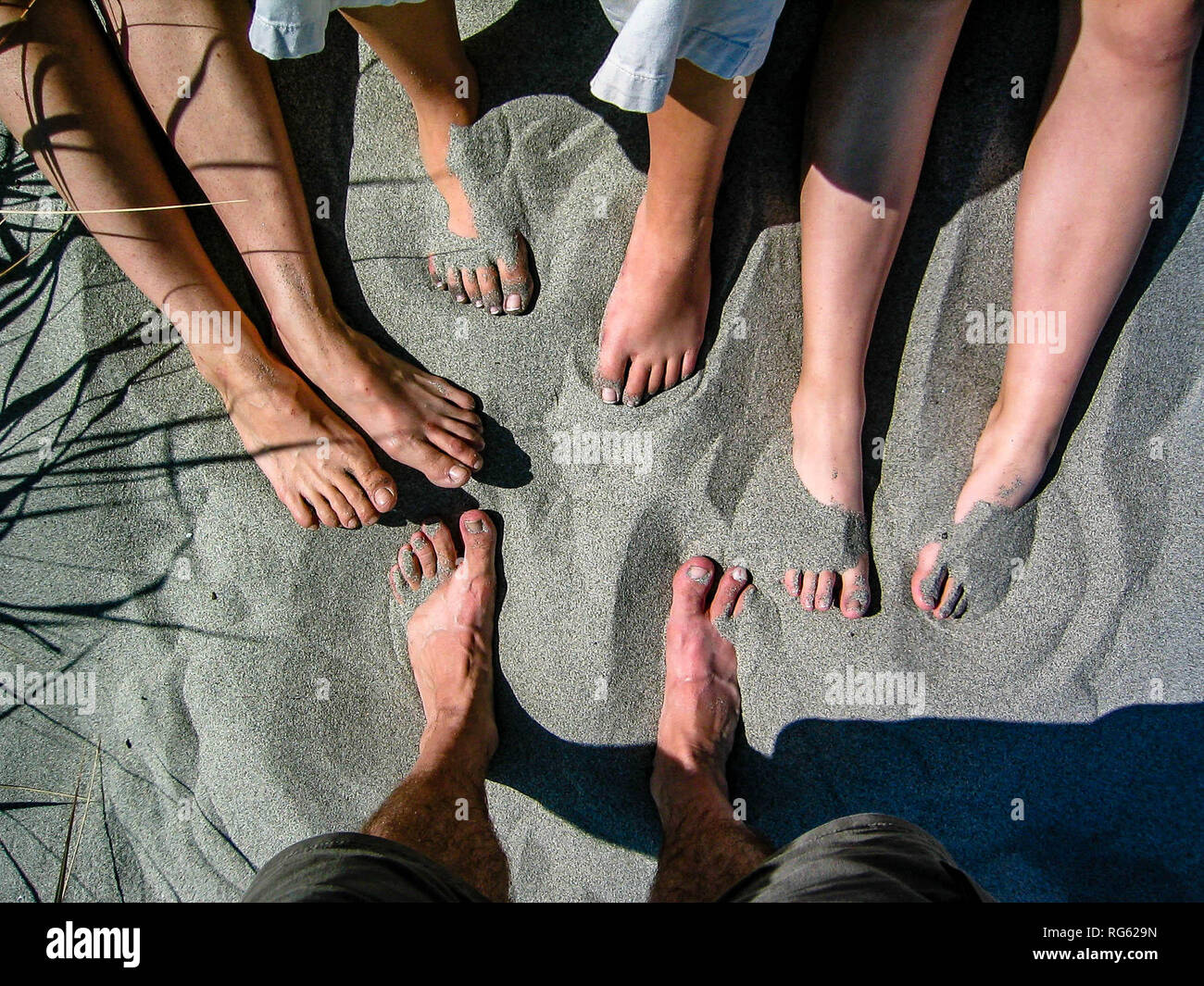 Four people's feet in sand Stock Photo - Alamy