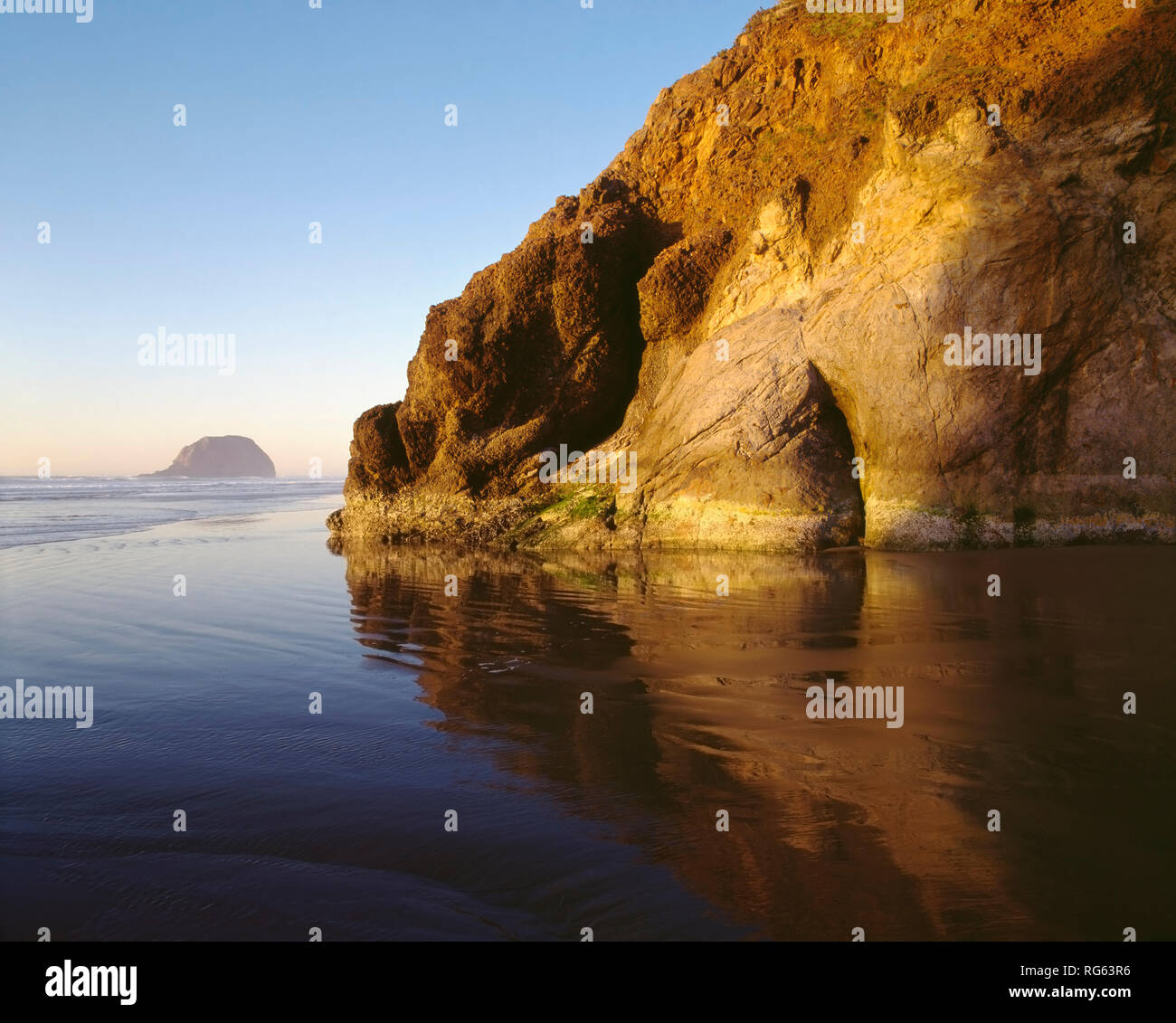 USA, Oregon, Arcadia Beach State Park, Evening light warms sandstone ...