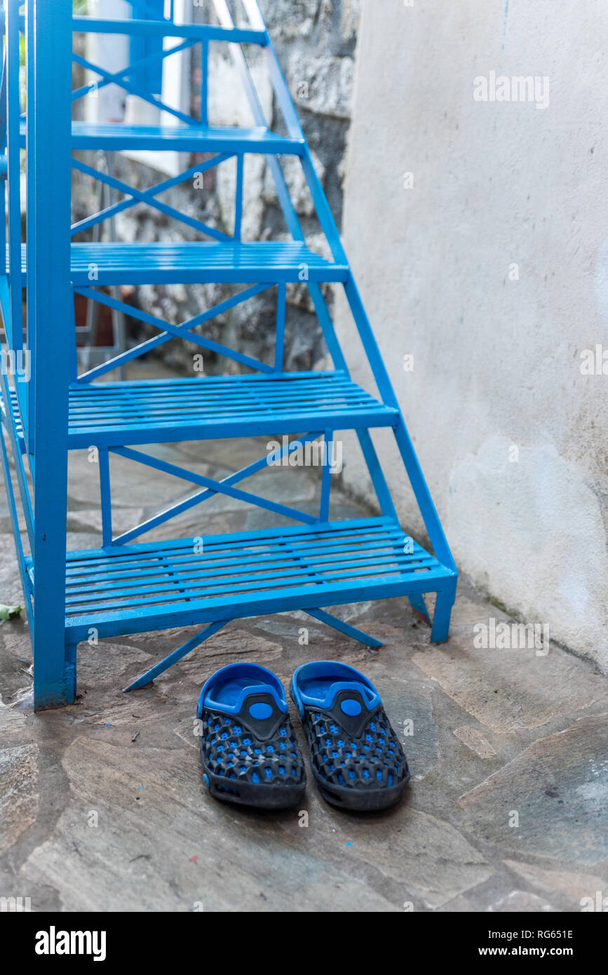 Pair of blue rubber shoes in front of blue metal stairs in Greek ...