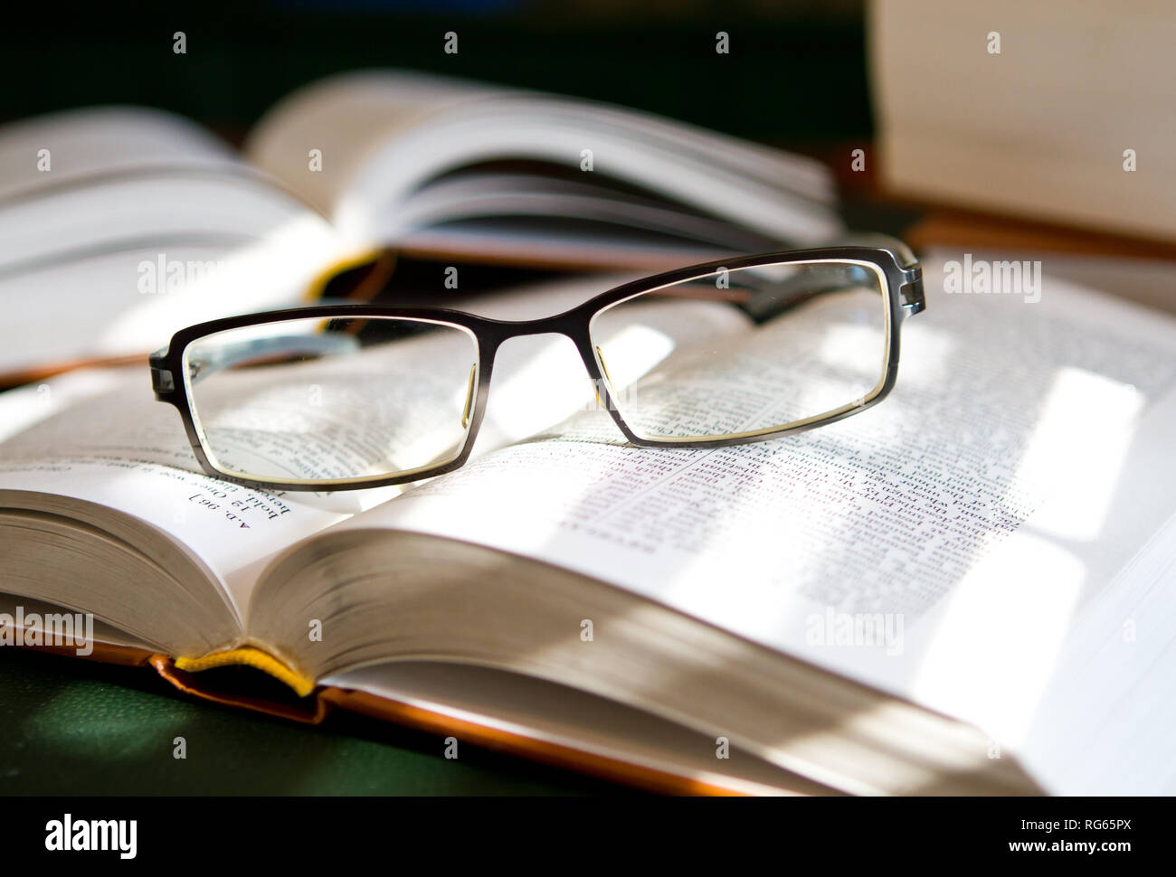 Reading glass on open book with books as background Stock Photo - Alamy