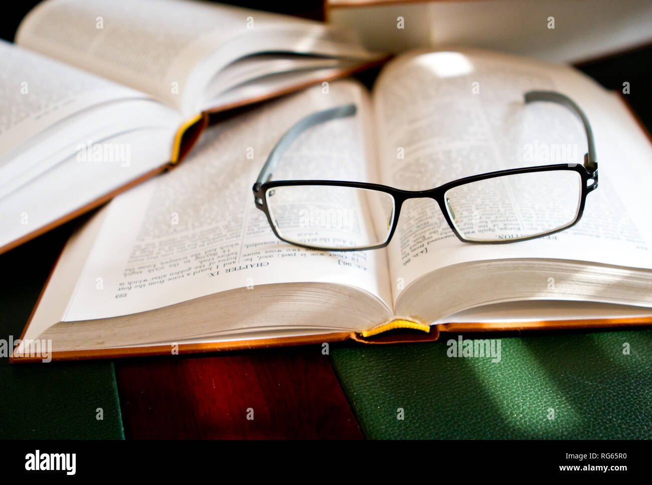 Reading glass on open book with books as background Stock Photo - Alamy