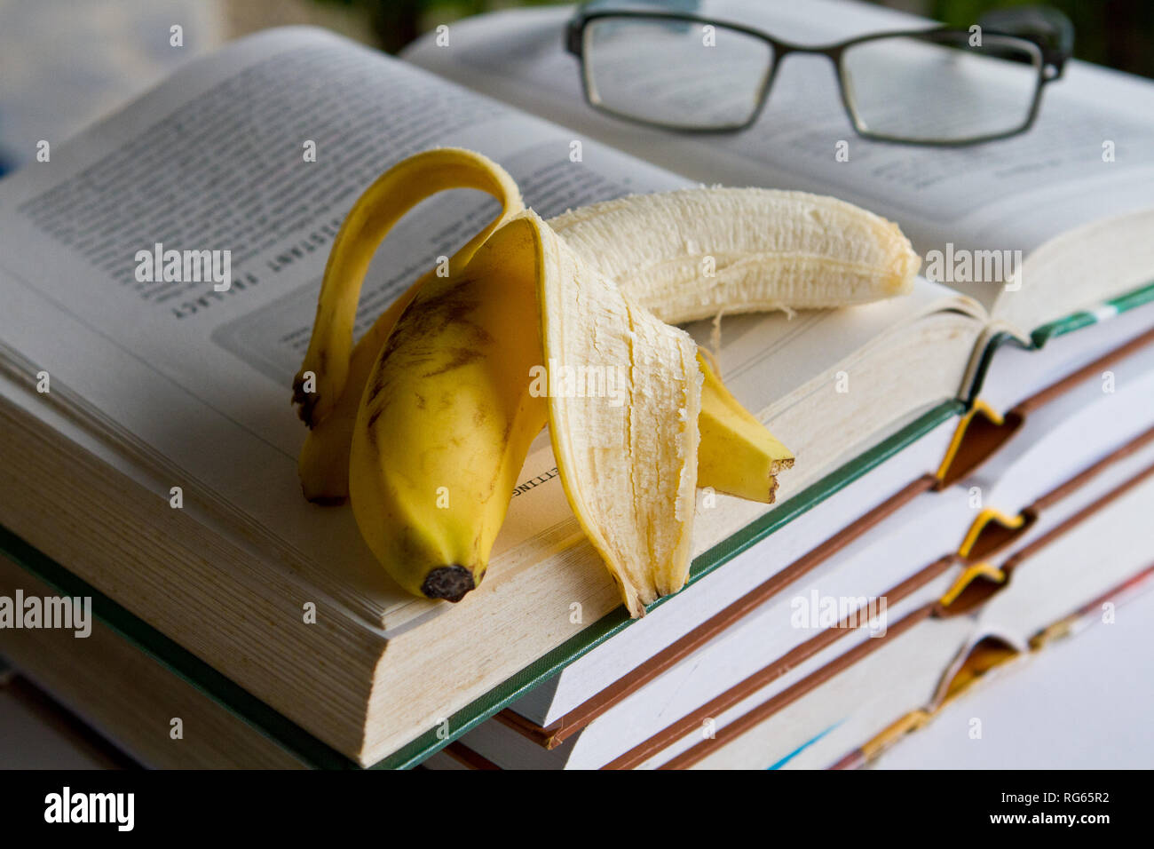 Books, reading glass and half-eaten banana Stock Photo - Alamy
