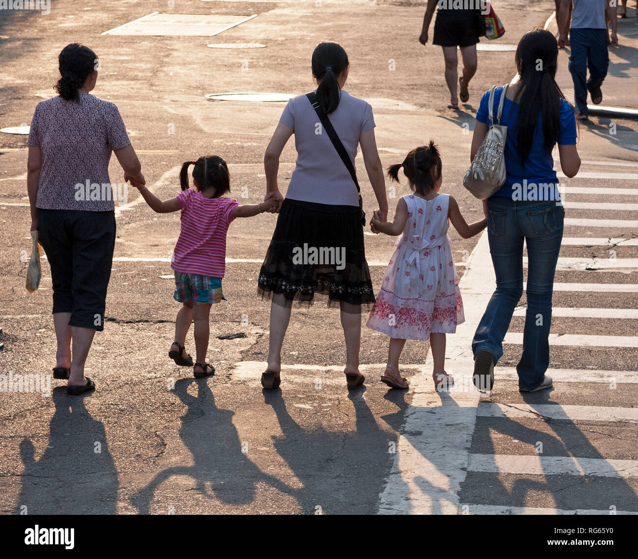 Women and children hold hands while crossing a street in New York City ...