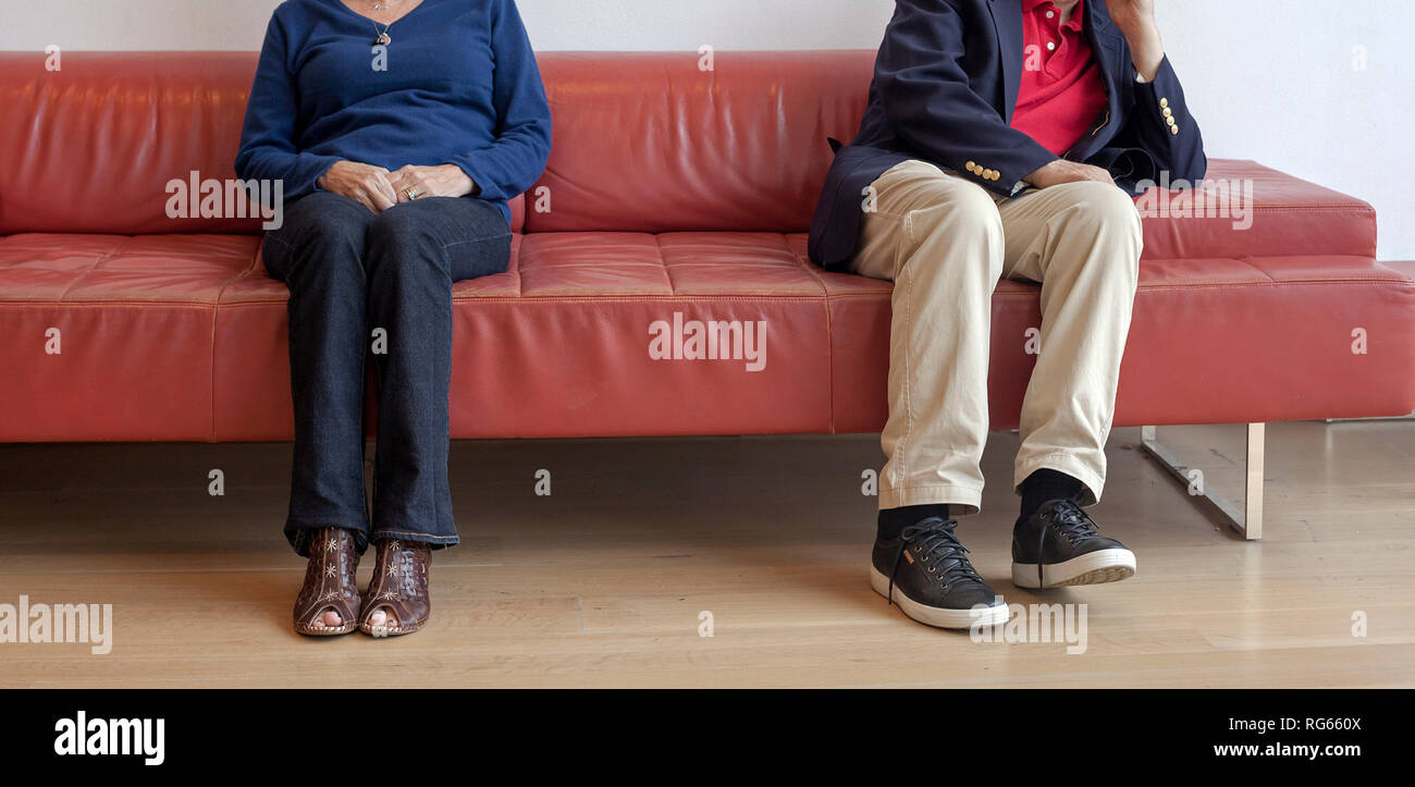 A woman and a man sit on a bench with space between them Stock Photo ...