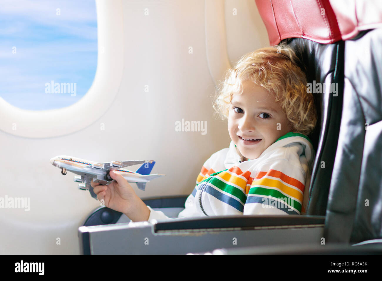 Child in airplane. Kid in air plane sitting in window seat. Flight ...