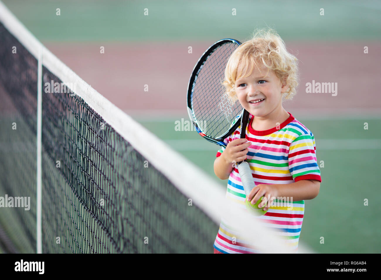 Child playing tennis on indoor court. Little boy with tennis racket and ...