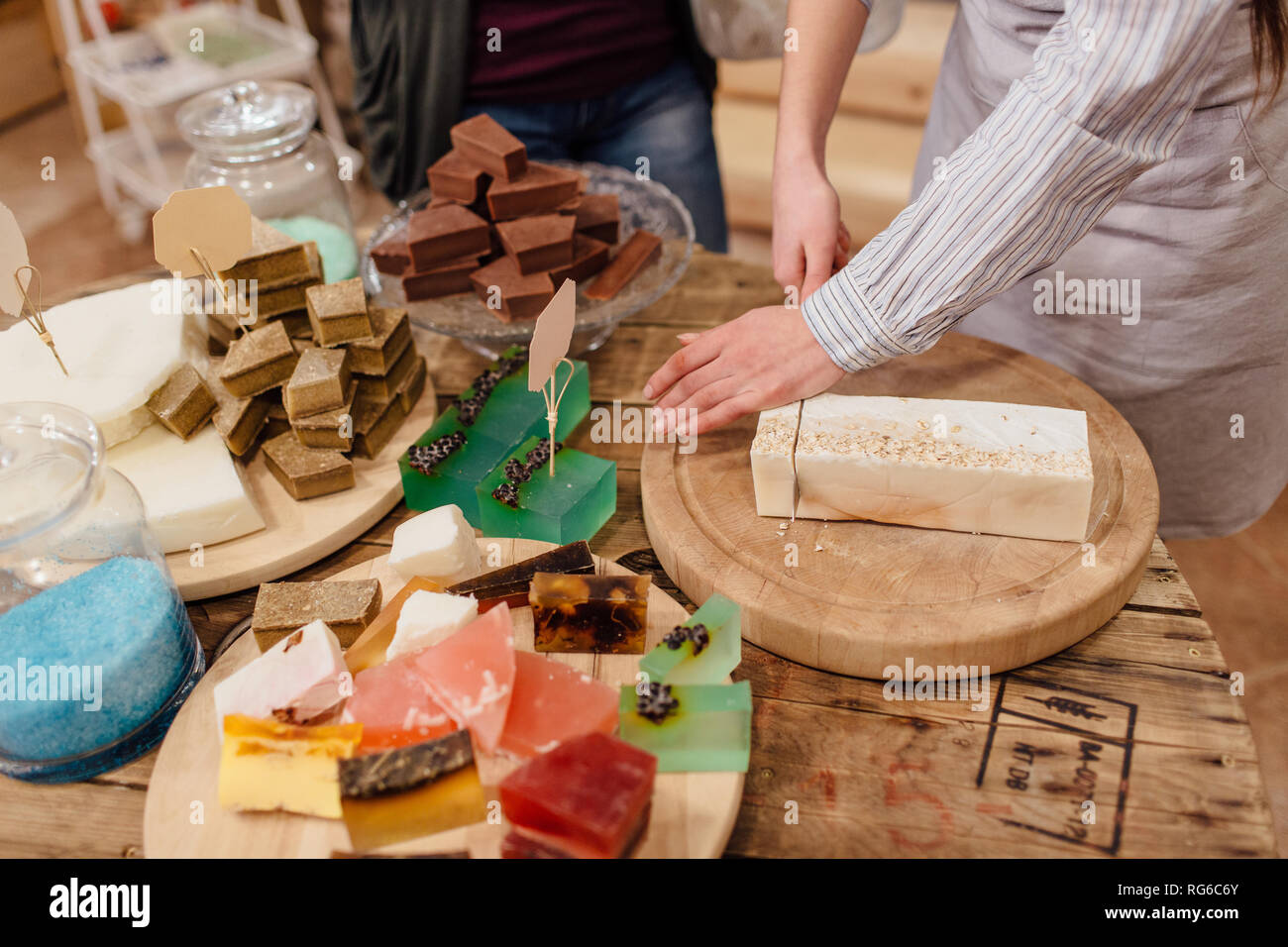 Shop assistant cutting bars of natural soap for customer in package ...