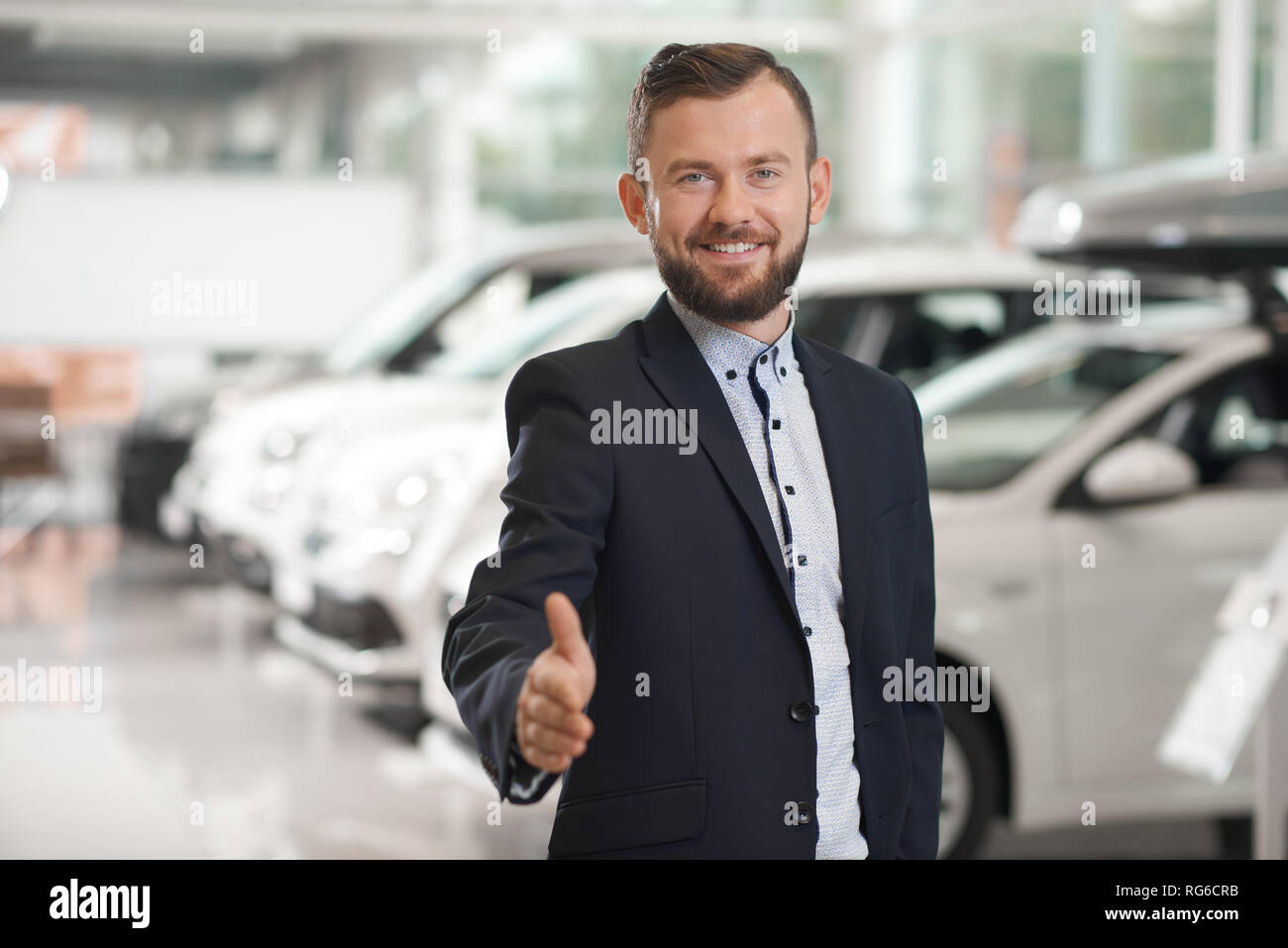 Handsome manager of car dealership looking at camera, smiling, posing ...