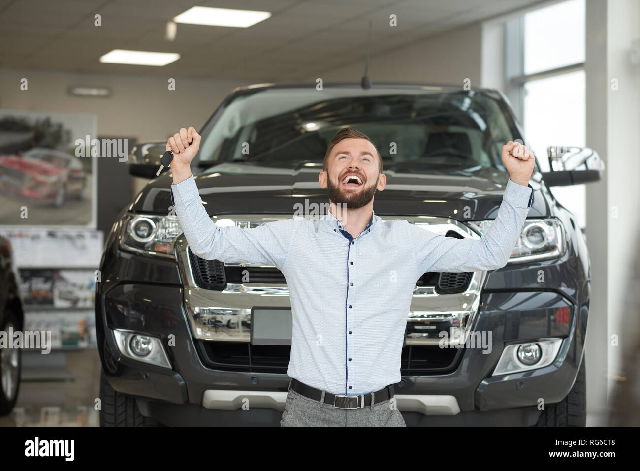 Happy owner of new car looking up, smiling with opened mouth and ...