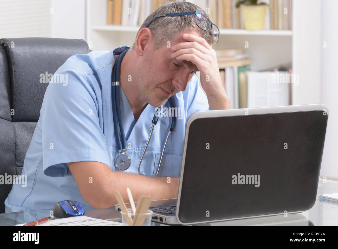 Overworked doctor sitting in his office Stock Photo - Alamy