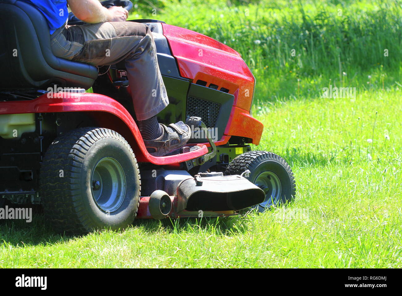 Gardener driving a riding lawn mower in a garden Stock Photo - Alamy