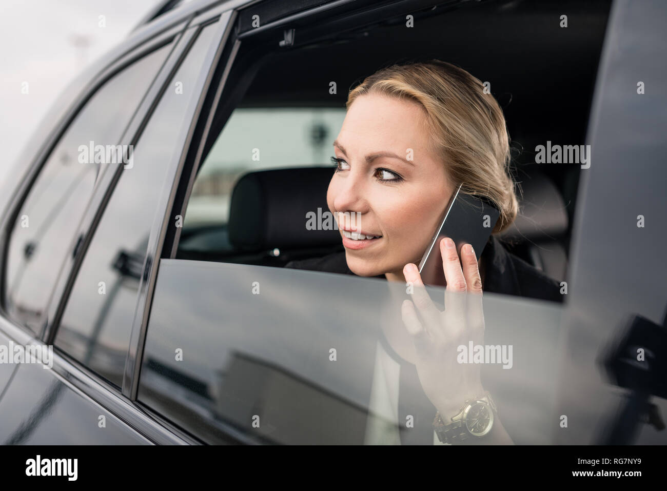 Businesswoman with cellphone looking outside the car window Stock Photo ...