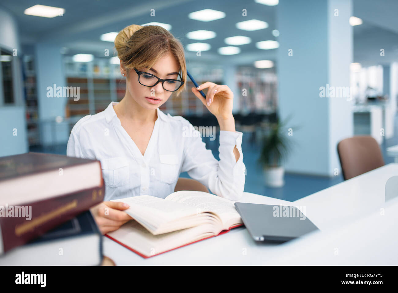 Pretty woman in glasses learning book in library. Female person in ...