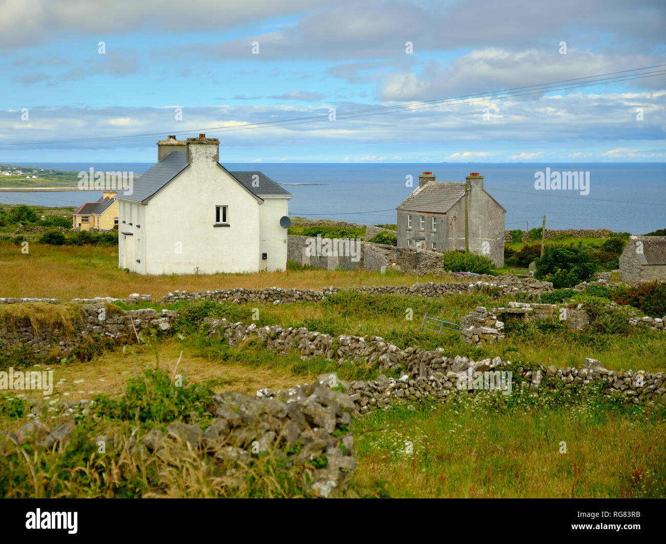 Irish country side scenery, with rock fences, little houses and ocean ...