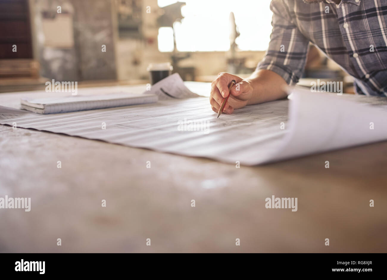 Craftsman leaning over a bench reading furniture design blueprints ...