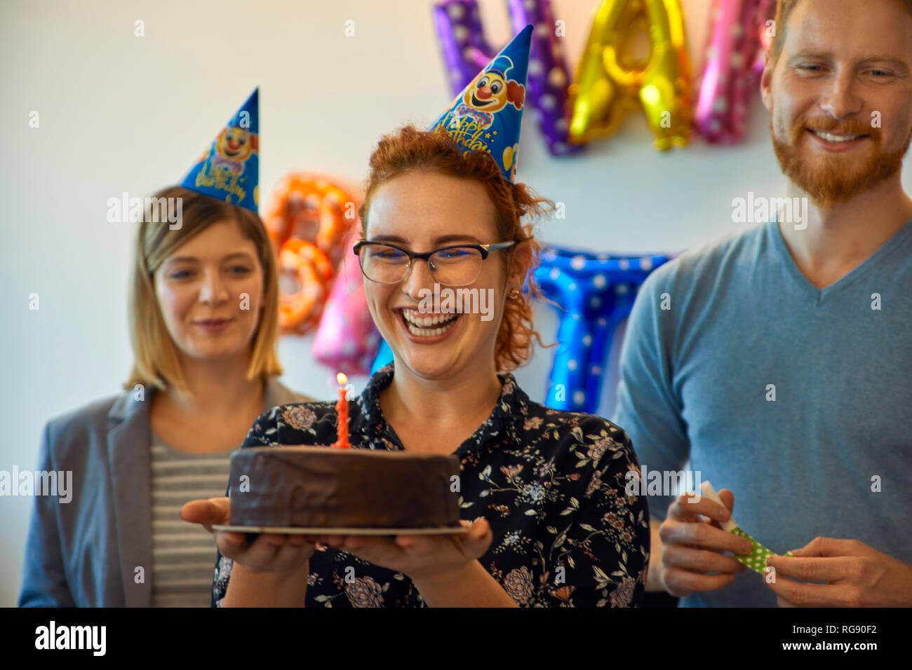 Colleagues having a birthday celebration in office with cake and party ...