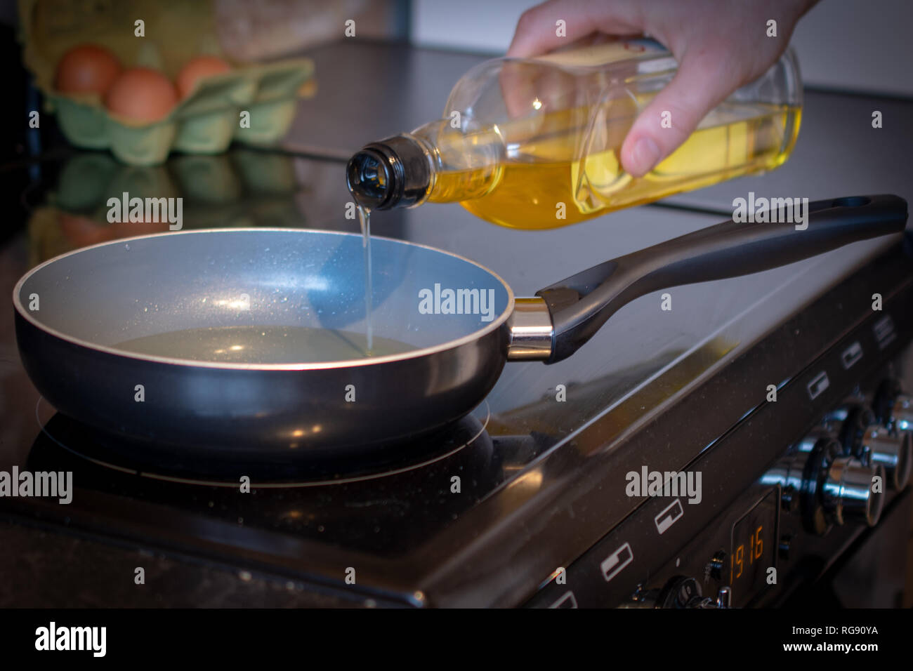 pouring cooking oil into a pan in preparation to cook breakfast over a ...