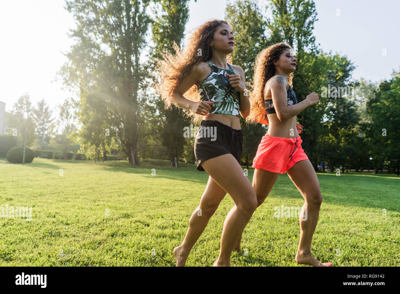 Twin sisters jogging together in a park at evening twilight Stock Photo ...