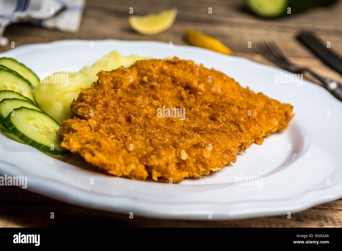 Chicken fried schnitzel with mashed potatoes and lemon on wood table ...