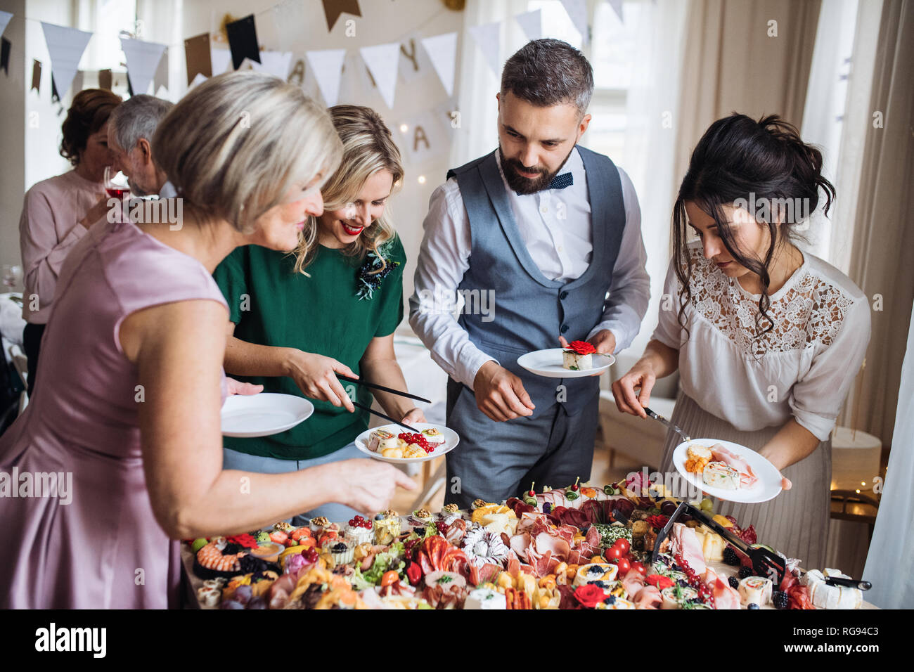 A multigeneration family putting food on plates on a indoor family ...