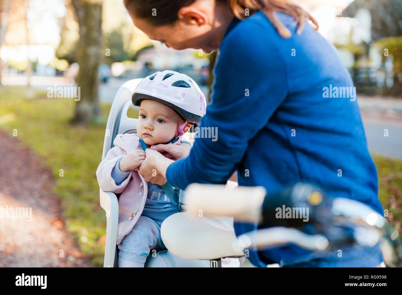 Mother and daughter riding bicycle, baby wearing helmet sitting in ...