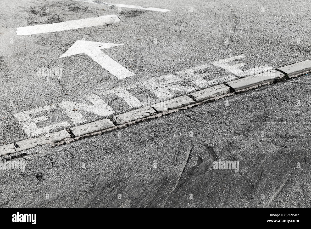 French text Entrance, white road marking over dark urban asphalt ...