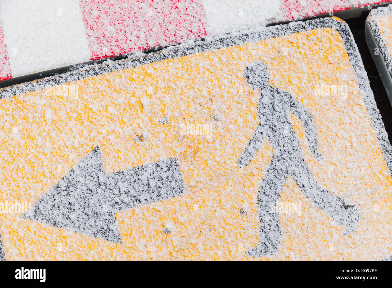Pedestrians bypass direction. Yellow road sign with snow, close up ...