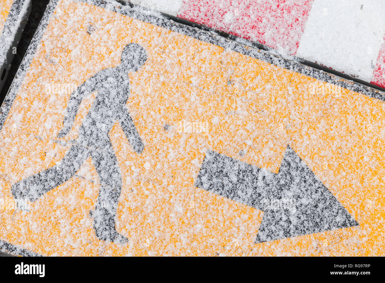 Pedestrians bypass direction. Yellow road sign covered with snow, close ...