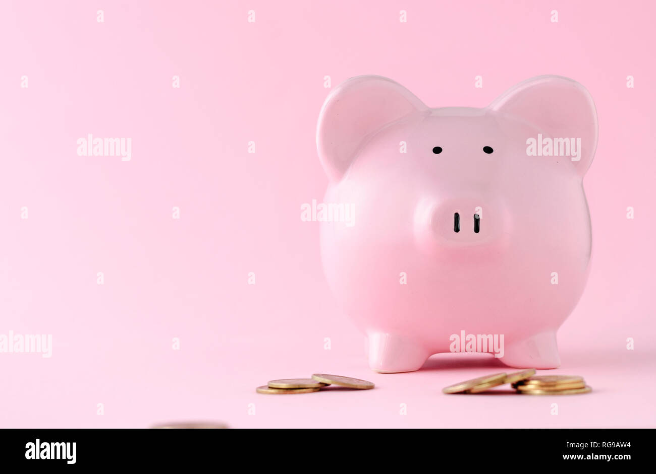 Pink ceramic piggy bank over matching pink background with copy space ...