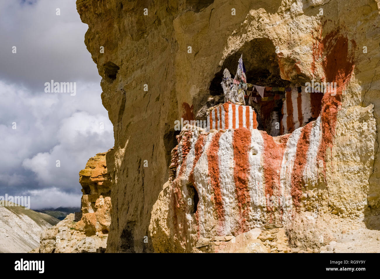 A red and white painted buddhist cave shrine, located in a rock cliff ...