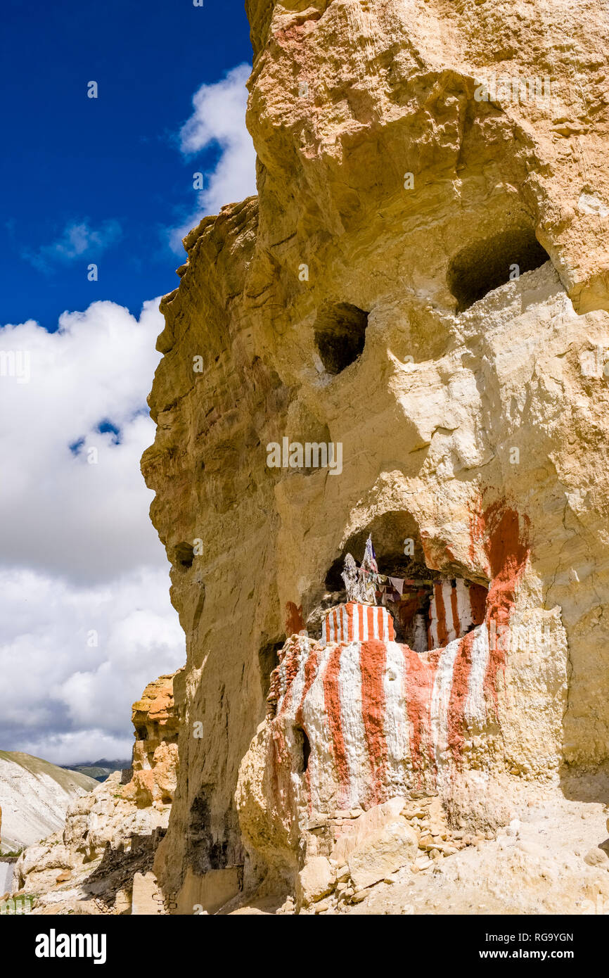 A red and white painted buddhist cave shrine, located in a rock cliff ...