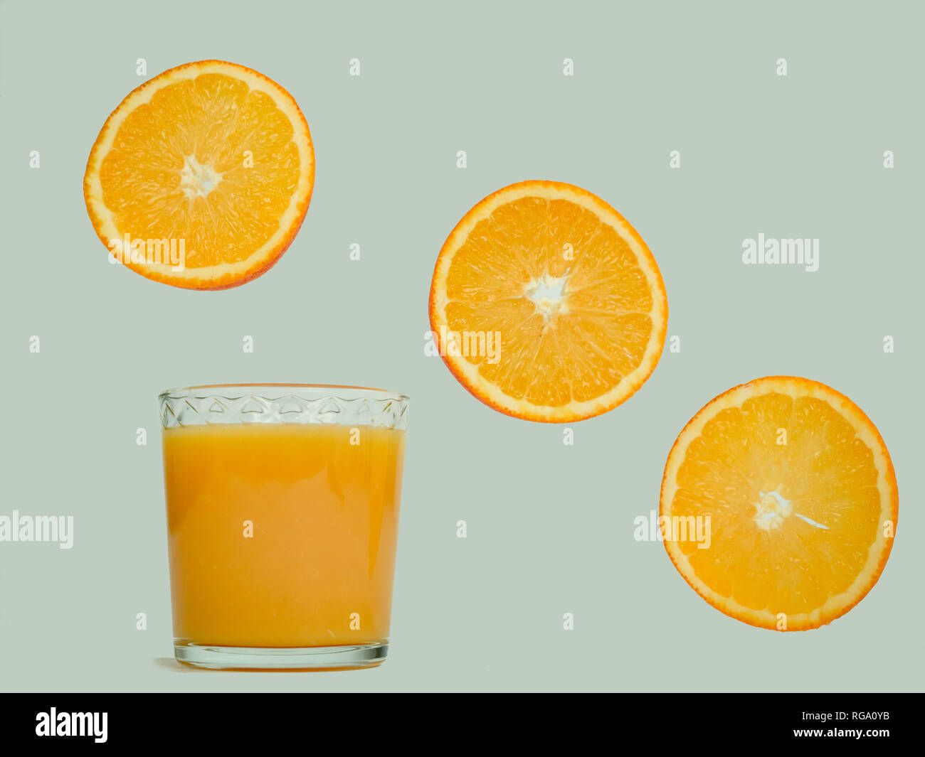 Glass with fresh orange juice, flying orange slices on a white ...