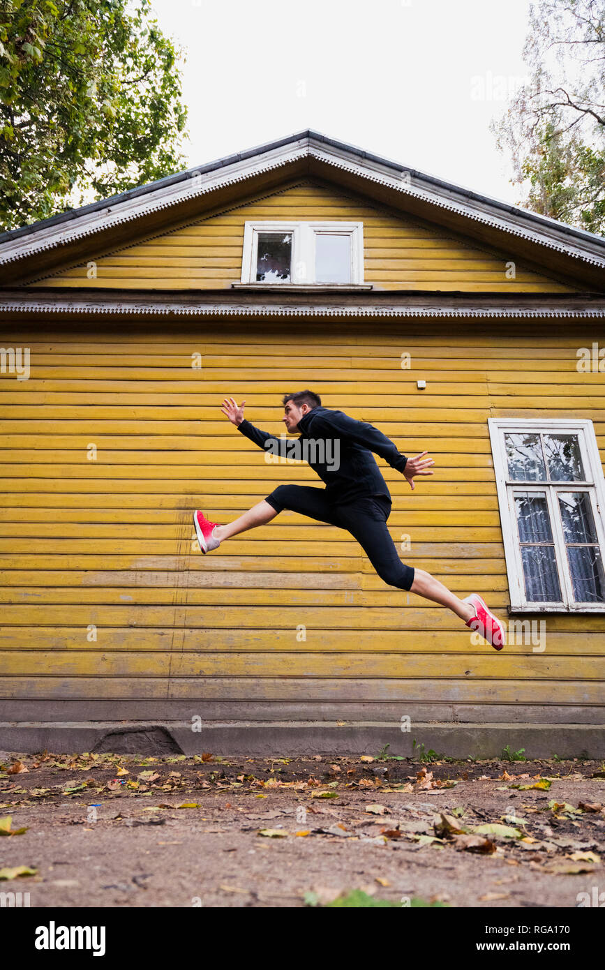 Dynamic athlete jumping in front of a yellow wood house Stock Photo - Alamy