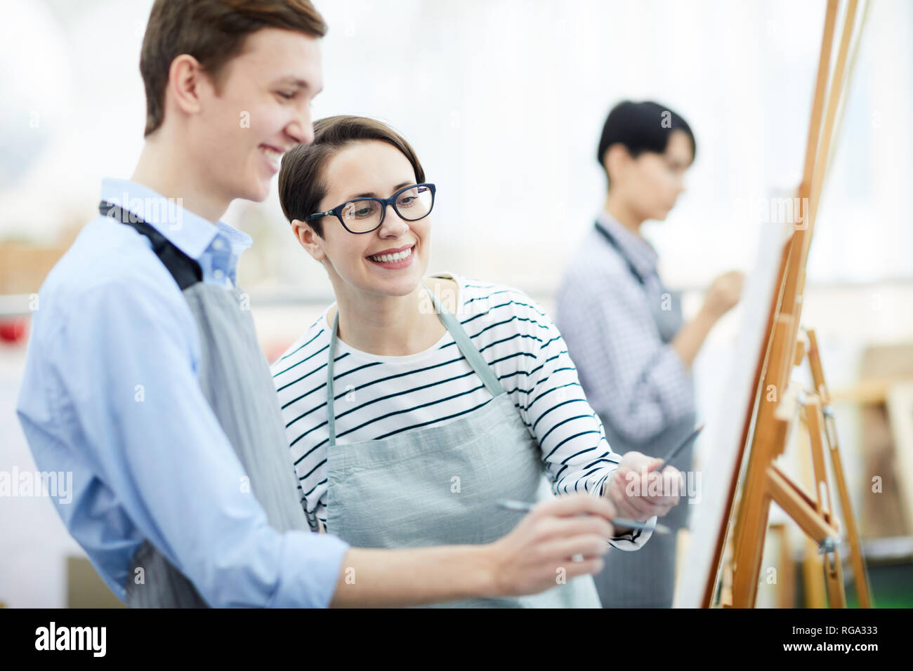 Portrait of female art teacher helping student painting picture on ...
