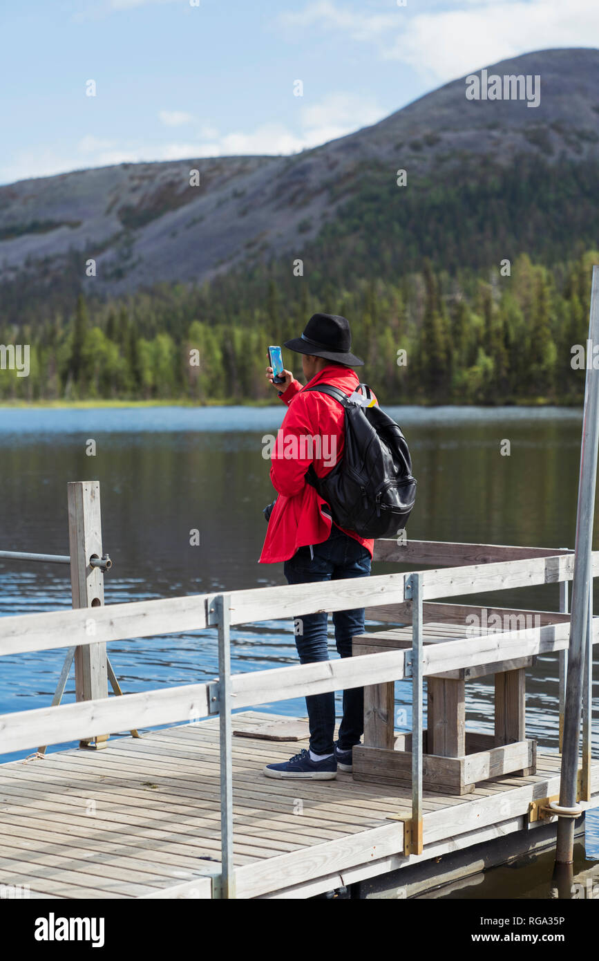 Finland, Lapland, man taking cell phone picture at the lakeside Stock ...