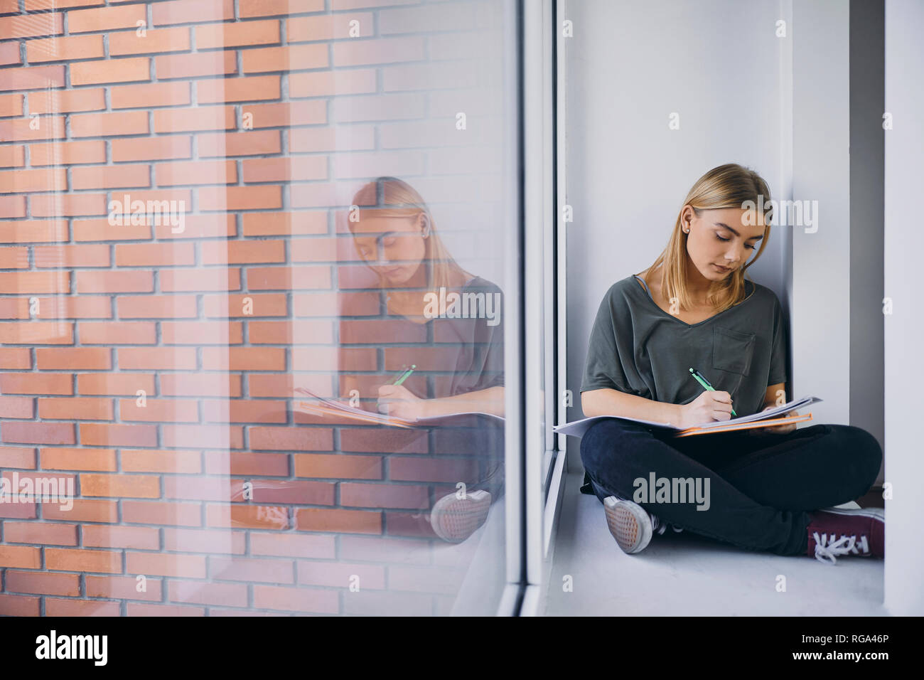 Student sitting at the window in hallway learning Stock Photo - Alamy