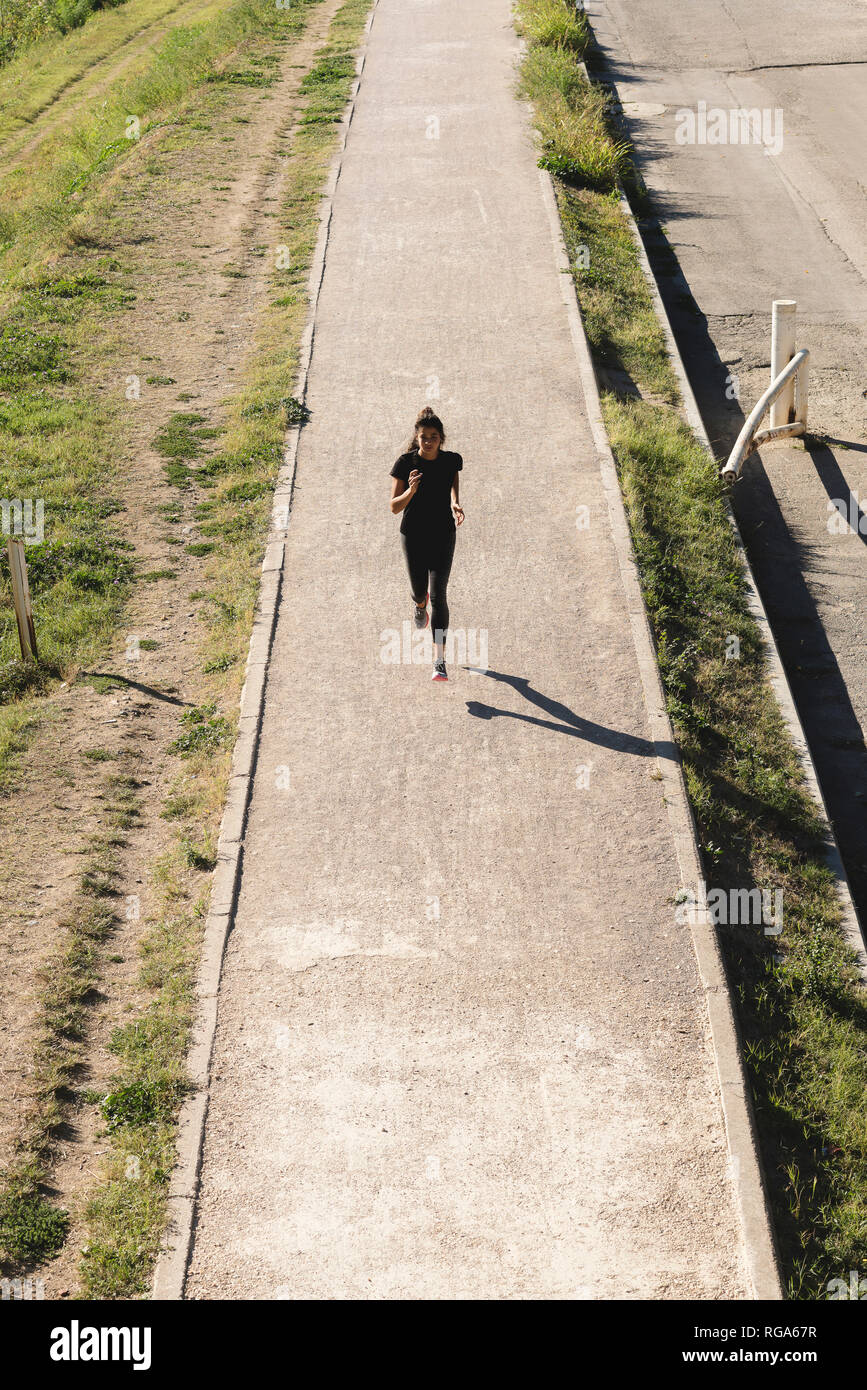 Sportive young woman running on a path Stock Photo - Alamy