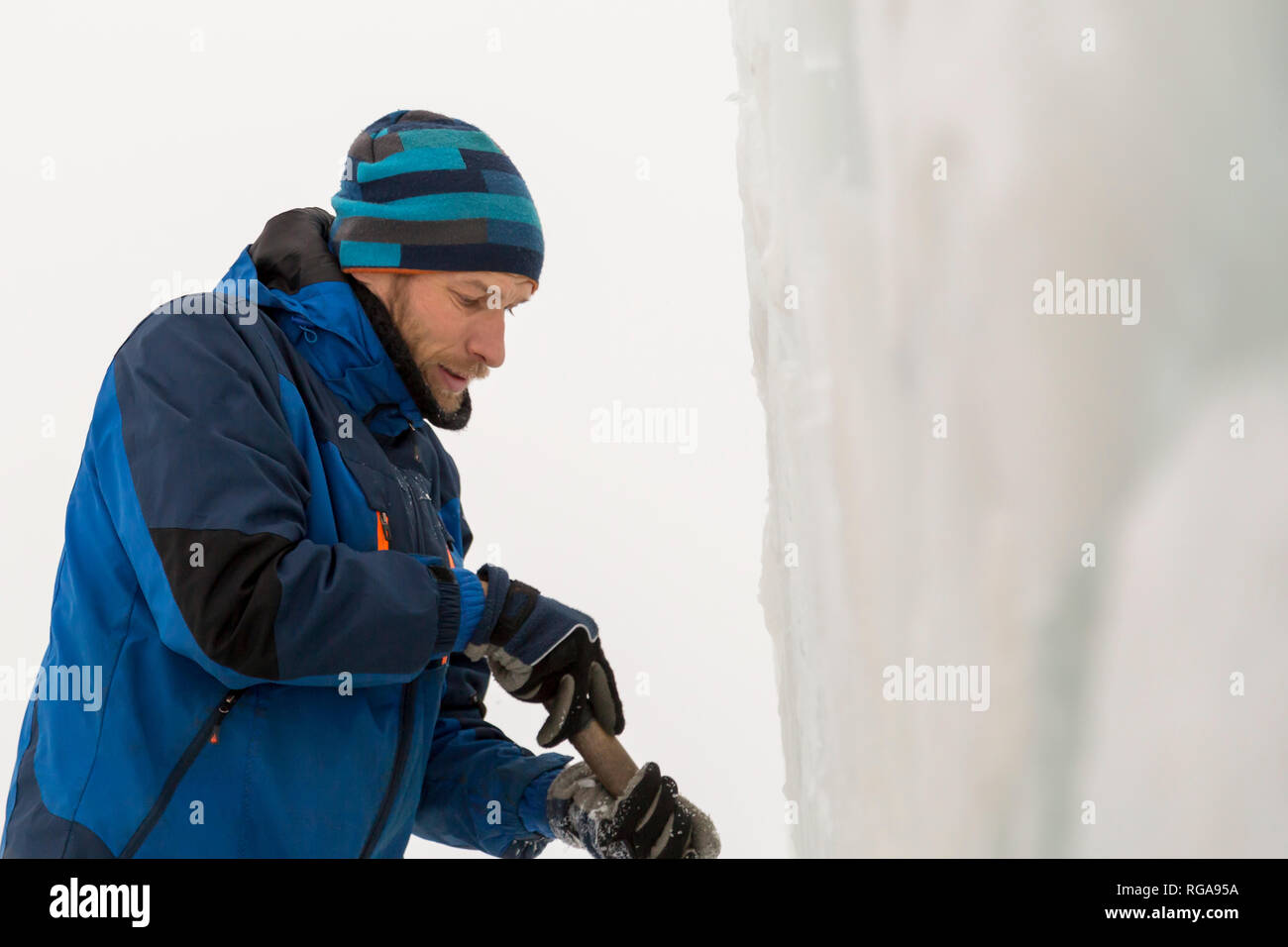 The sculptor cuts an ice figure out of an ice block with a chisel Stock ...