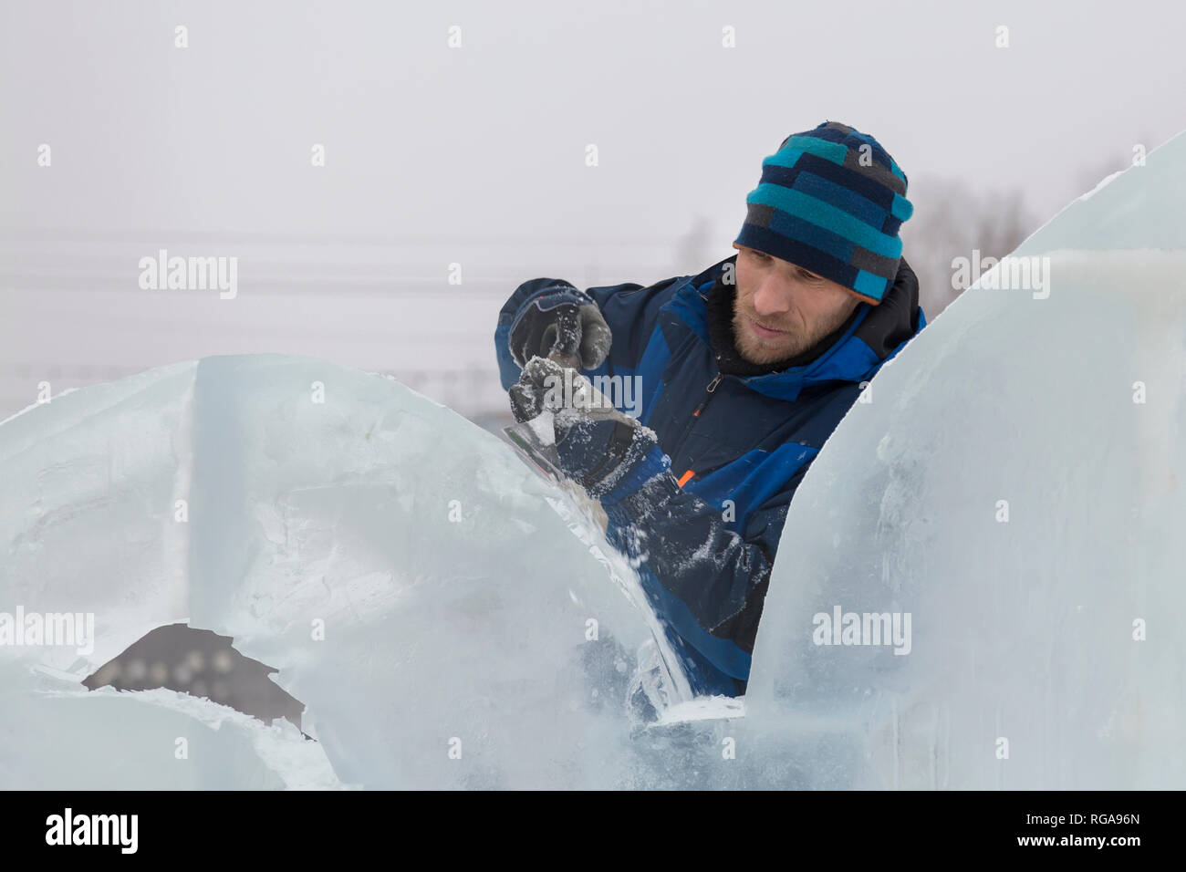 The sculptor cuts an ice figure out of ice with a chisel for Christmas ...