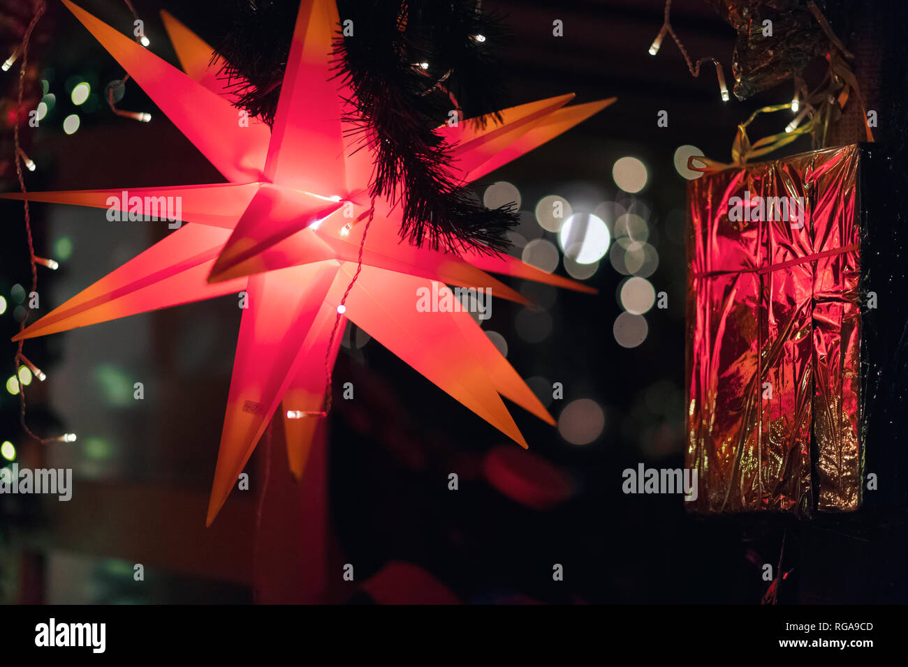 Lighted red Moravian star and gleaming red Christmas present Stock ...