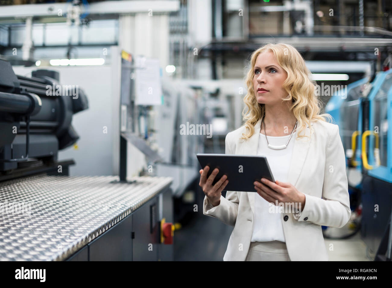 Woman with tablet at machine in factory shop floor looking around Stock ...