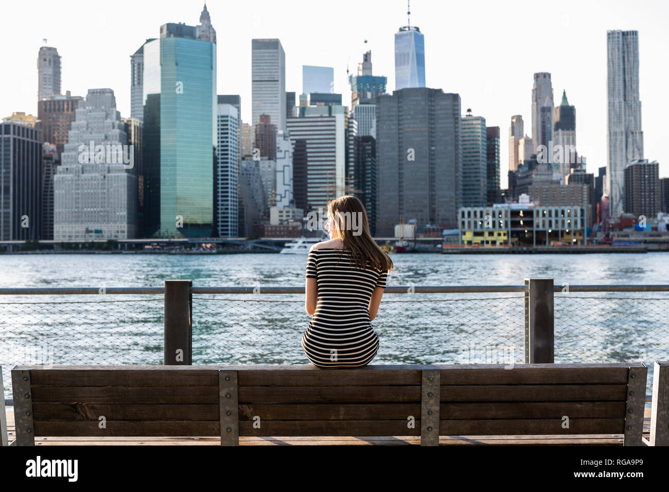 USA, New York, Brooklyn, back view of woman sitting on bench in front ...