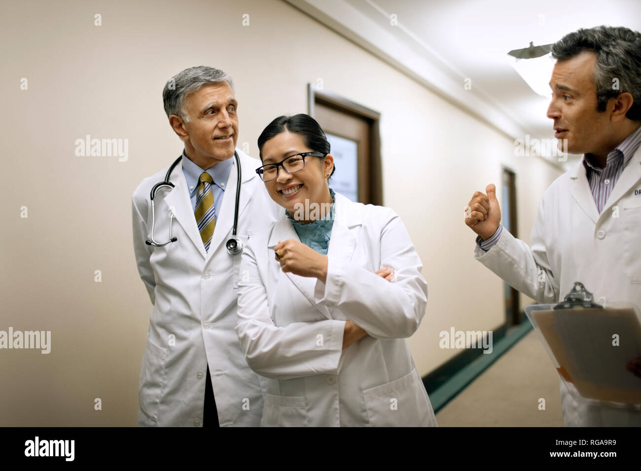 Medical colleagues laughing and talking in the corridor of a hospital ...