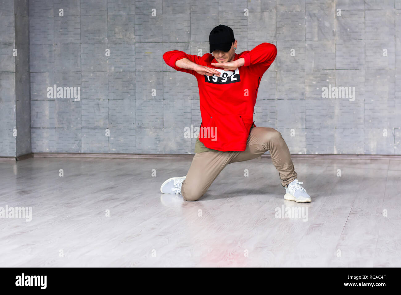 Young dancer posing on grey floor. Stylish hip-hop dancer making ...
