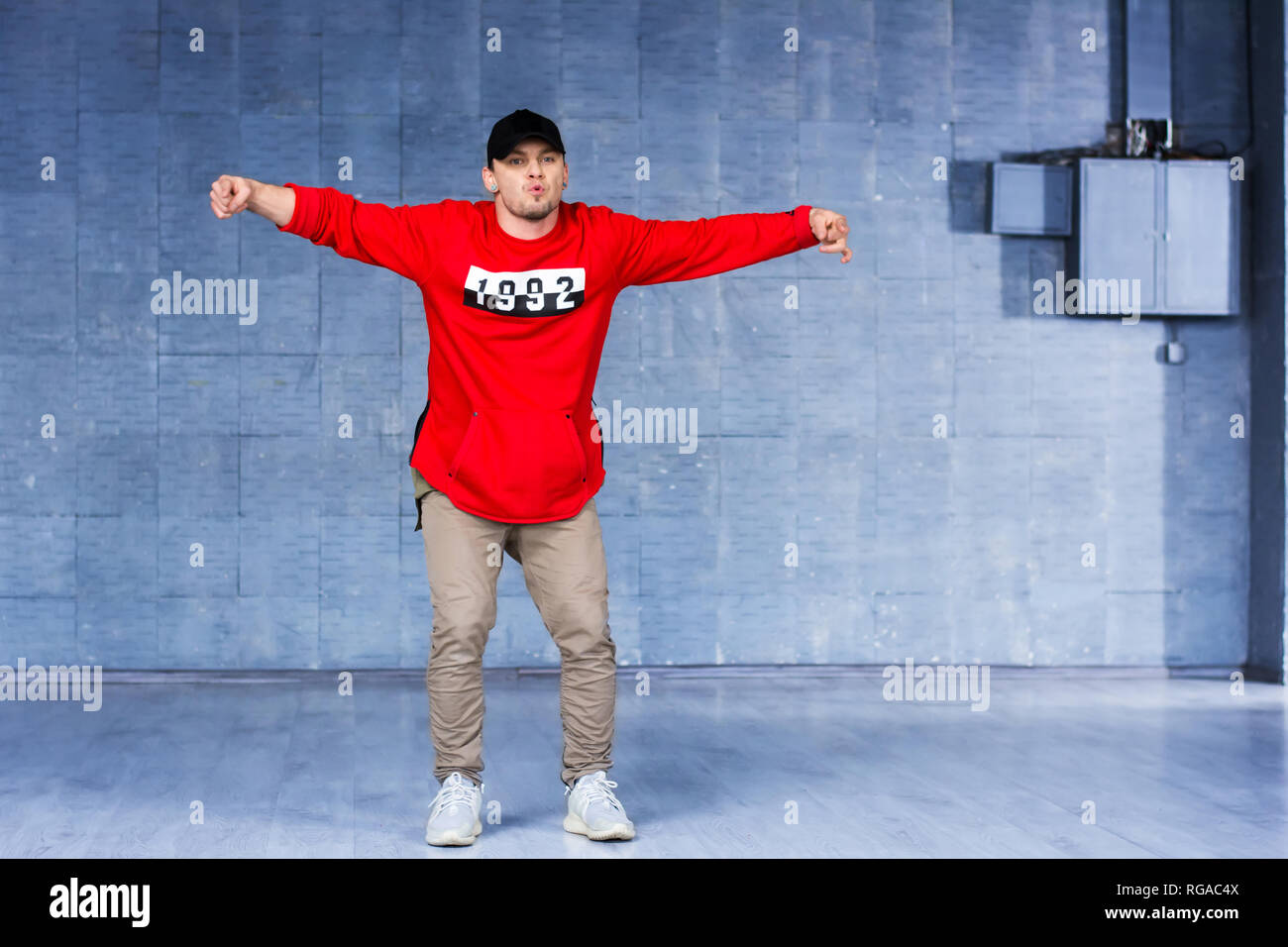 Young rapper is dancing. Attractive guy in modern casual clothes posing ...