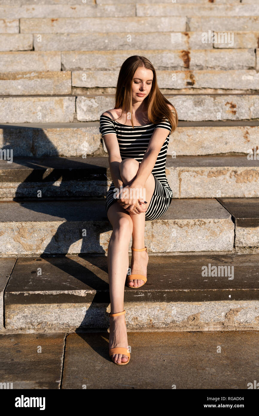 Portrait of young woman sitting on stairs enjoying sunset Stock Photo ...