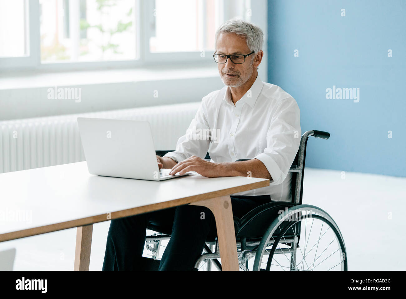 Handicapped manager in a wheelchair, working in office Stock Photo - Alamy