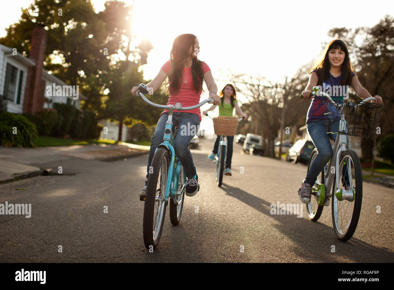Three friends cycling down the road together Stock Photo - Alamy