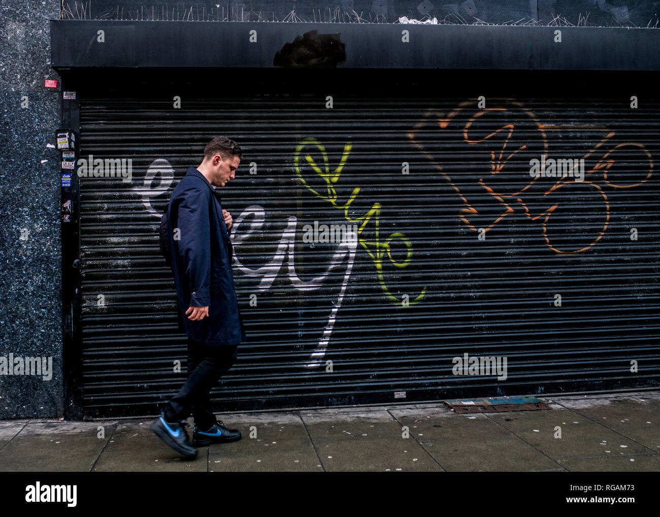Man walking past roller blind with graffiti hi-res stock photography ...